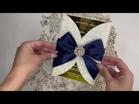 Elegant Gold Acrylic invitation with ivory embossed floral paper sleeve, navy blue bow pearl brooch