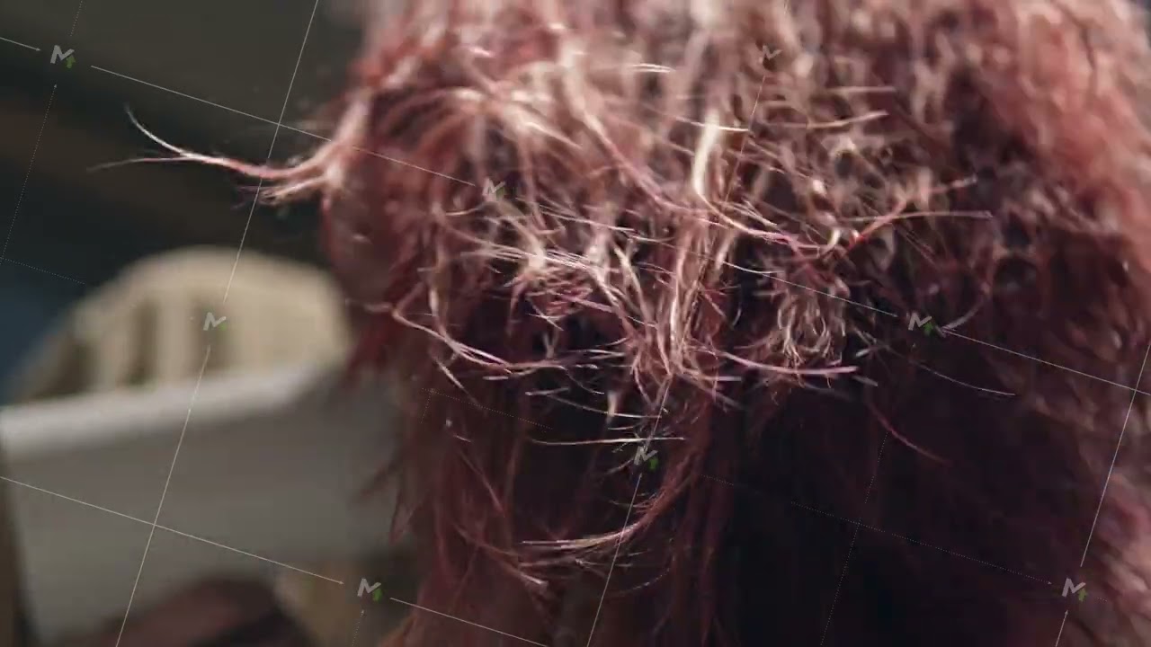 Slow motion portrait of a young Caucasian lady styling her long vibrant red hair in a home bathroom