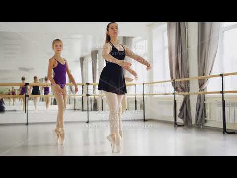 Two girls ballet dancers are practising dancing on tiptoes with their experienced teacher during