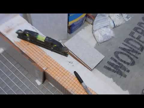 Measure and trim tiles for the bottom row of a shower