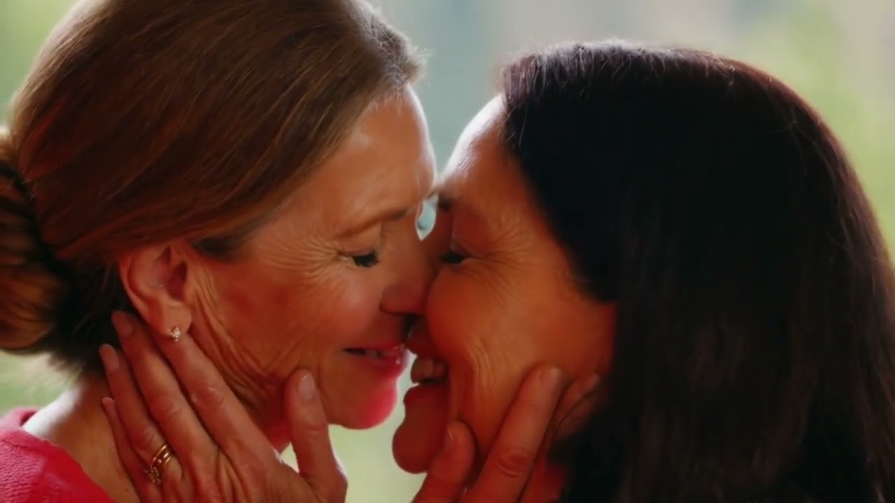 A vibrant party atmosphere with two women in chic lingerie sharing a flirtatious kiss