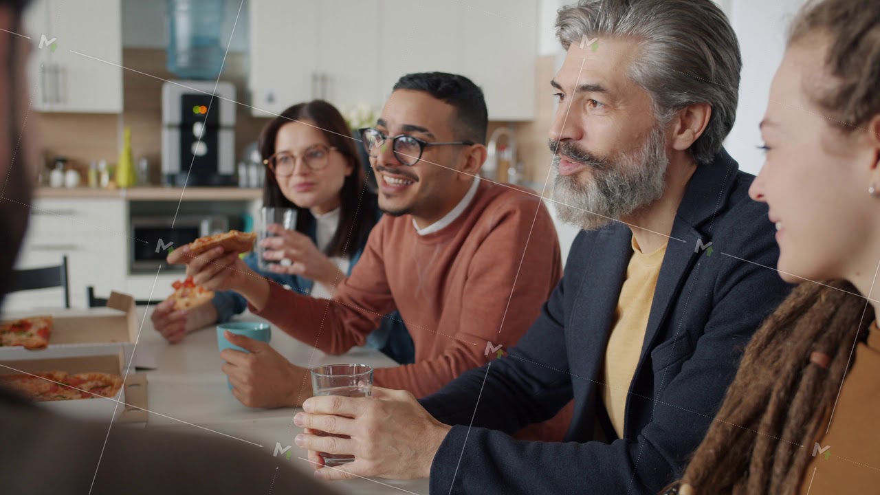 Diverse group of people coworkers talking and laughing eating pizza in workplace