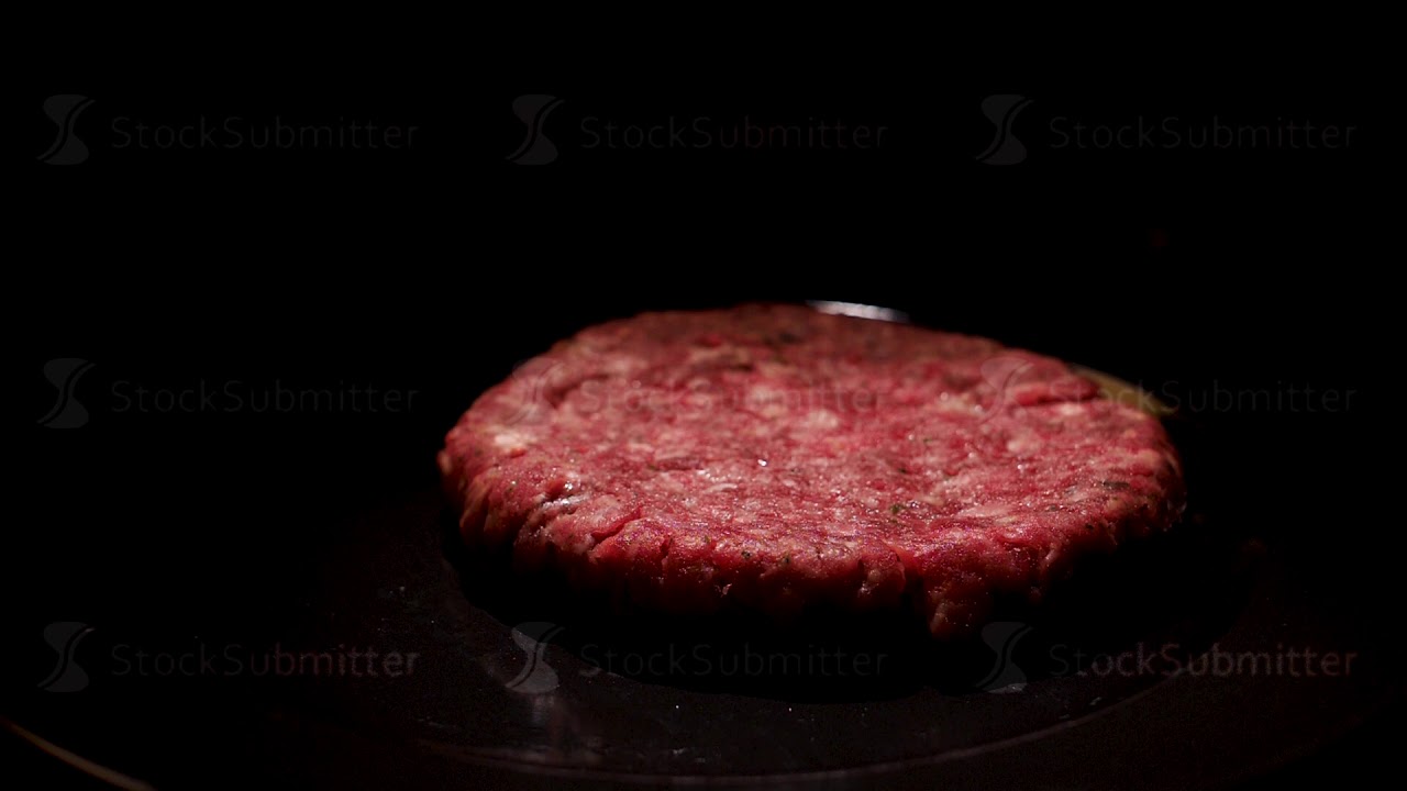 Close up of raw burger beef patty on black background, food and cooking concept. Stock footage