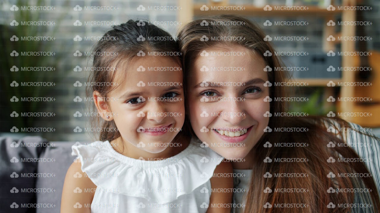 Portrait of happy young family mother and daughter smiling at camera indoors