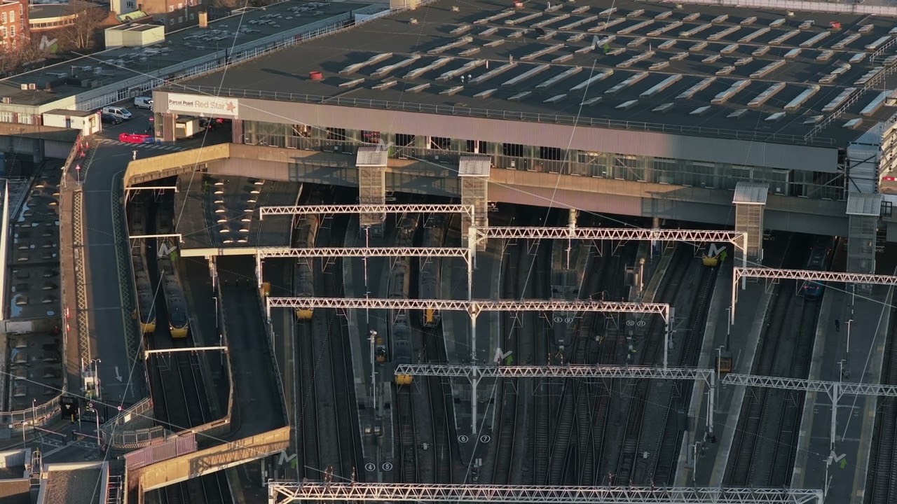 Aerial shot of London railway station with commuter trains moving on tracks and passengers walking