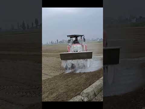 A guy in gas mask steering tractor to spray quicklime over farmland to improve the soil !