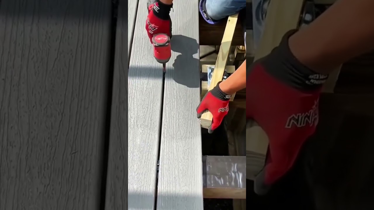 Installing composite decking boards using a power drill to fasten screws securely into the surface