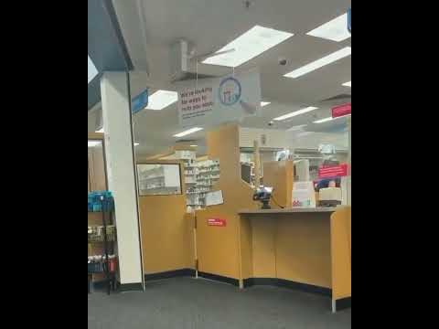 A man walks behind the CVS pharmacy counter & grabs prescription medication