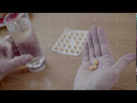 Close-up of round yellow pills in the palm of mature older person
