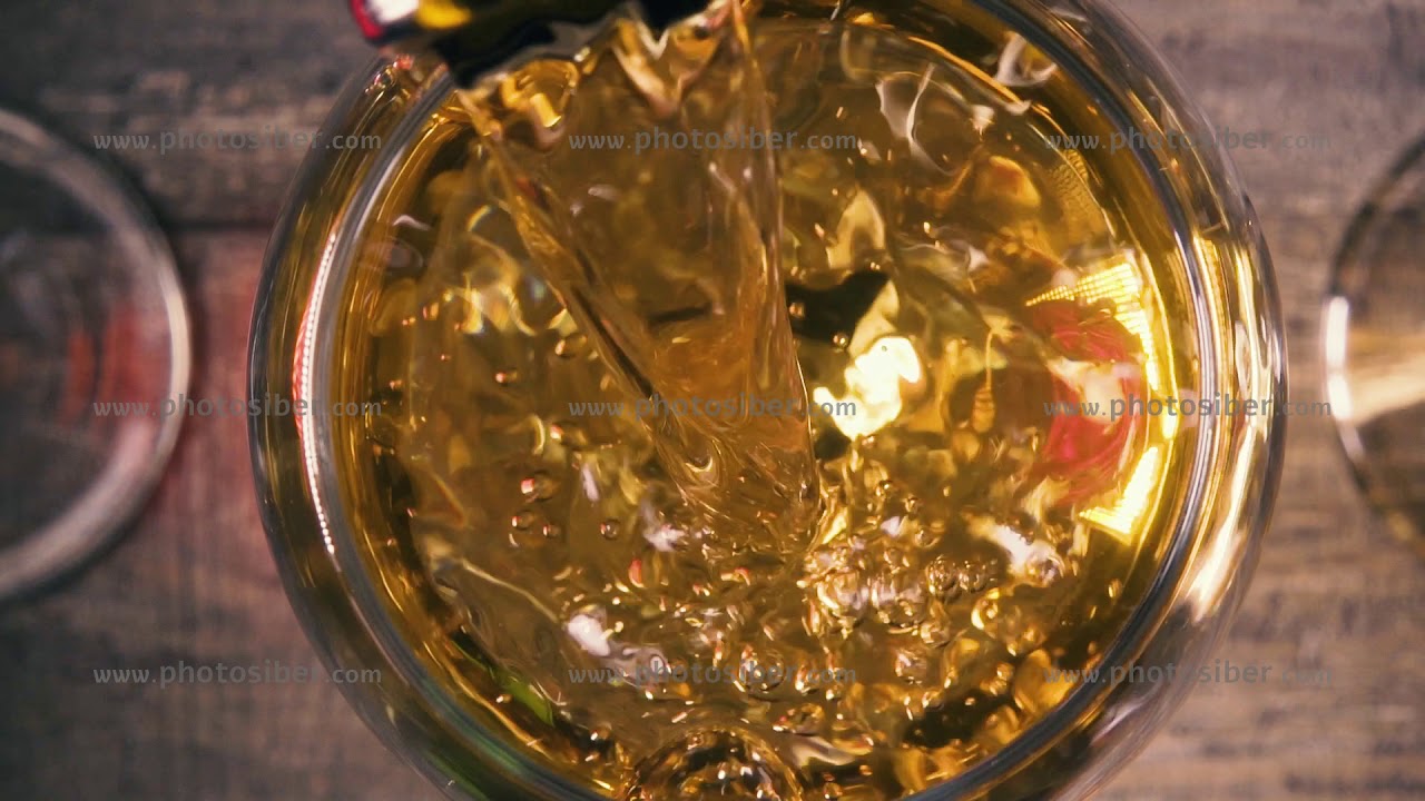 Slow motion pour white wine into a glass with reflection top view