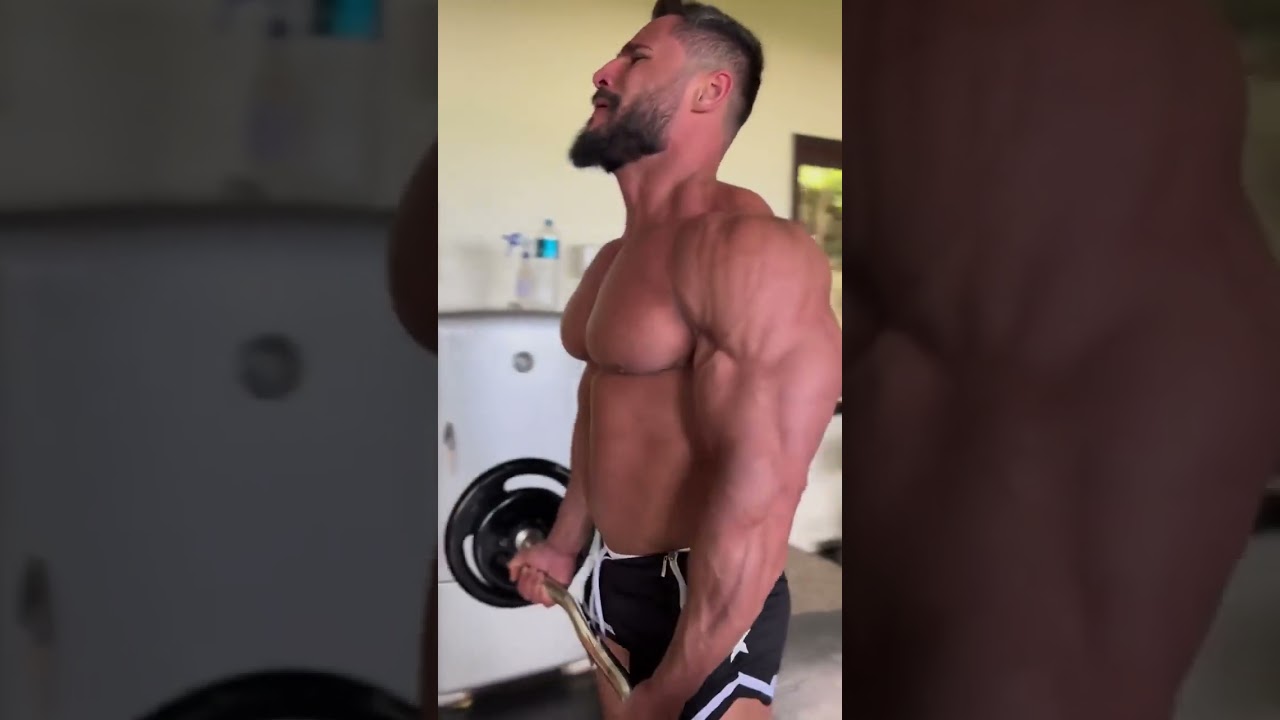 Muscle hunk Rodrigo Cavalcanti pumping iron in workout shorts
