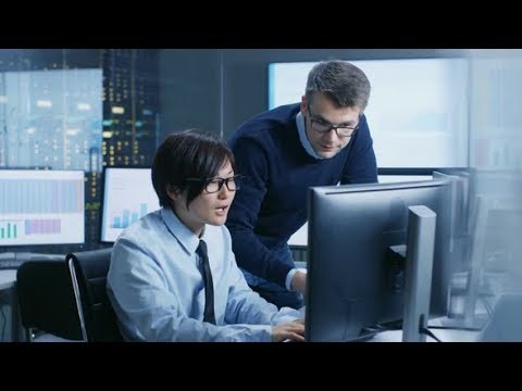 In the Data Mining Center Chief Statistician Consults His Young Assistant sits at His Workstation |