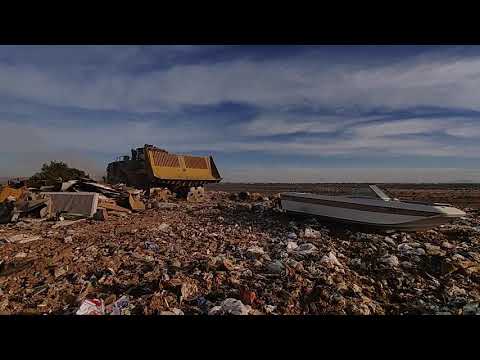 Caterpillar 836K Landfill Compactor crushing a boat.