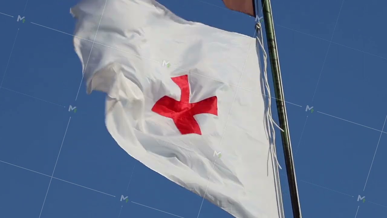 white flag with red cross developing in the wind