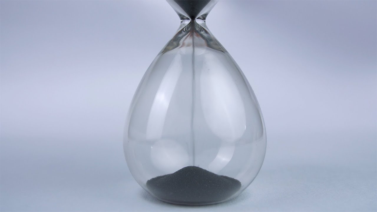 Extreme close up of a transparent hourglass with flowing black... | Indian Stock Footage | Knot9