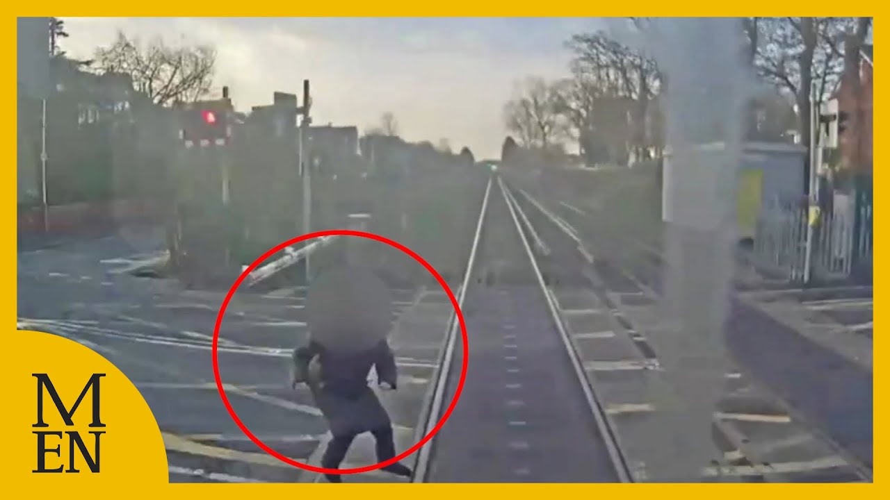 Chilling footage shows woman 'half a second' away from being hit by train at level crossing ...