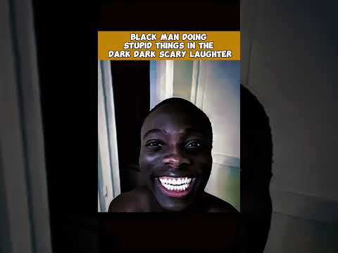 Black man smiles in dark laughing