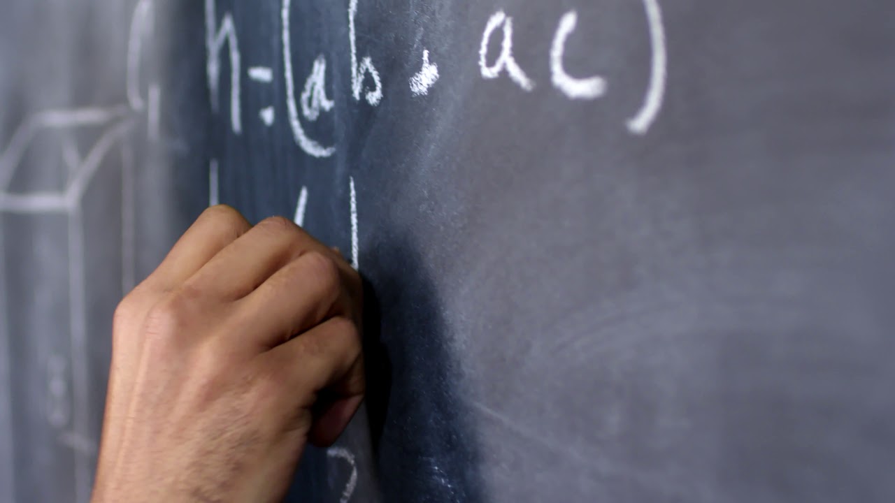 A Man Writing Mathematical Equation On A Blackboard
