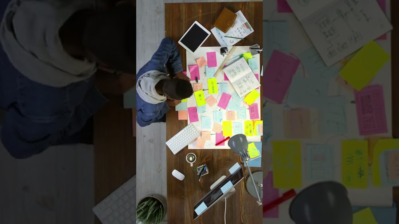 A Person Working On A Computer And Writing Notes On Pieces Of Papers