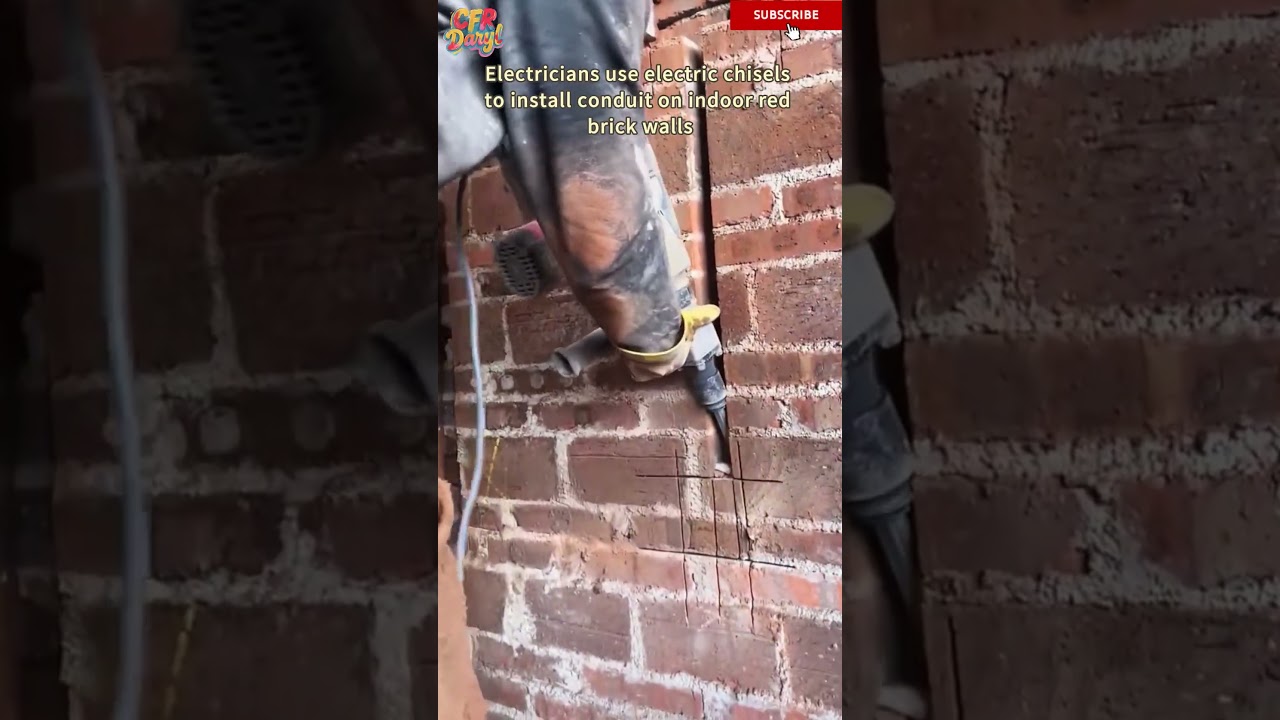 Electricians use electric chisels to install conduit on indoor red brick walls