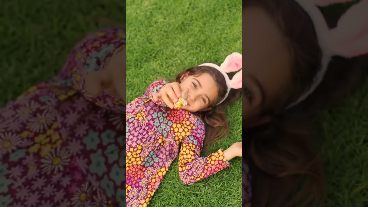little girl laying in the grass enjoying a chocolate bunny